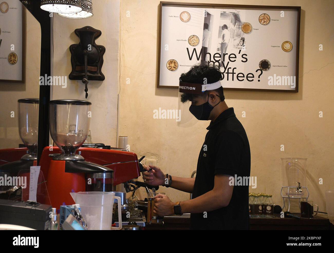 Cafe employee wearing face shield and mask works on the first day at ...
