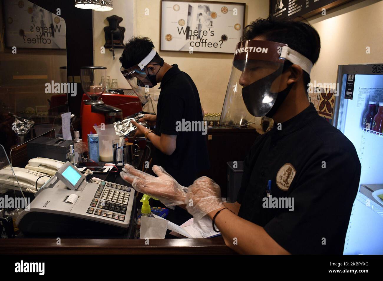 Cafe employee wearing face shield and mask works on the first day at ...
