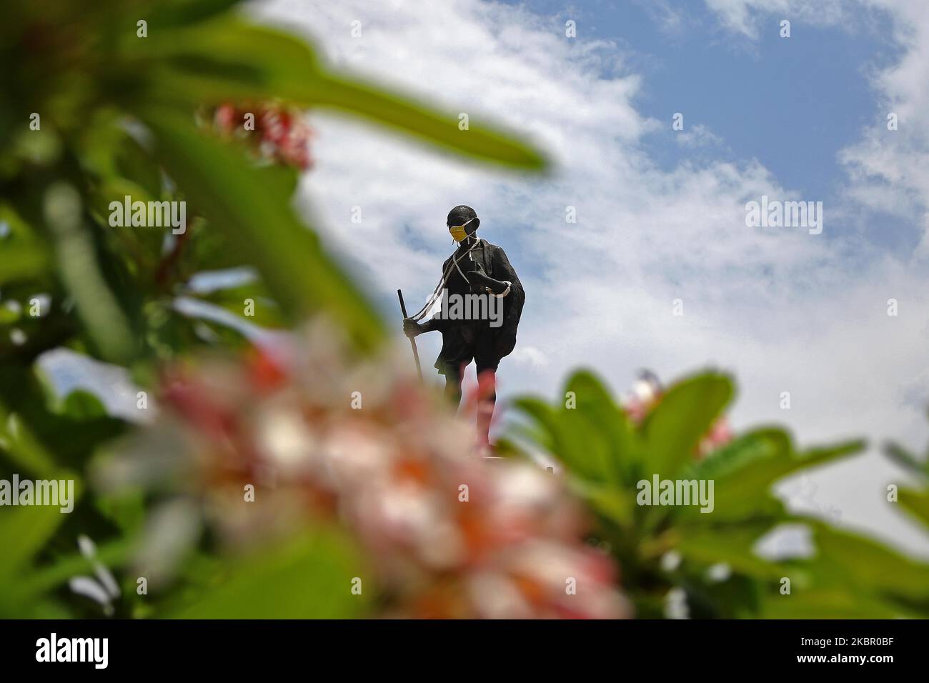 A mask is placed on a statue of Mahatma Gandhi to spread awareness ...