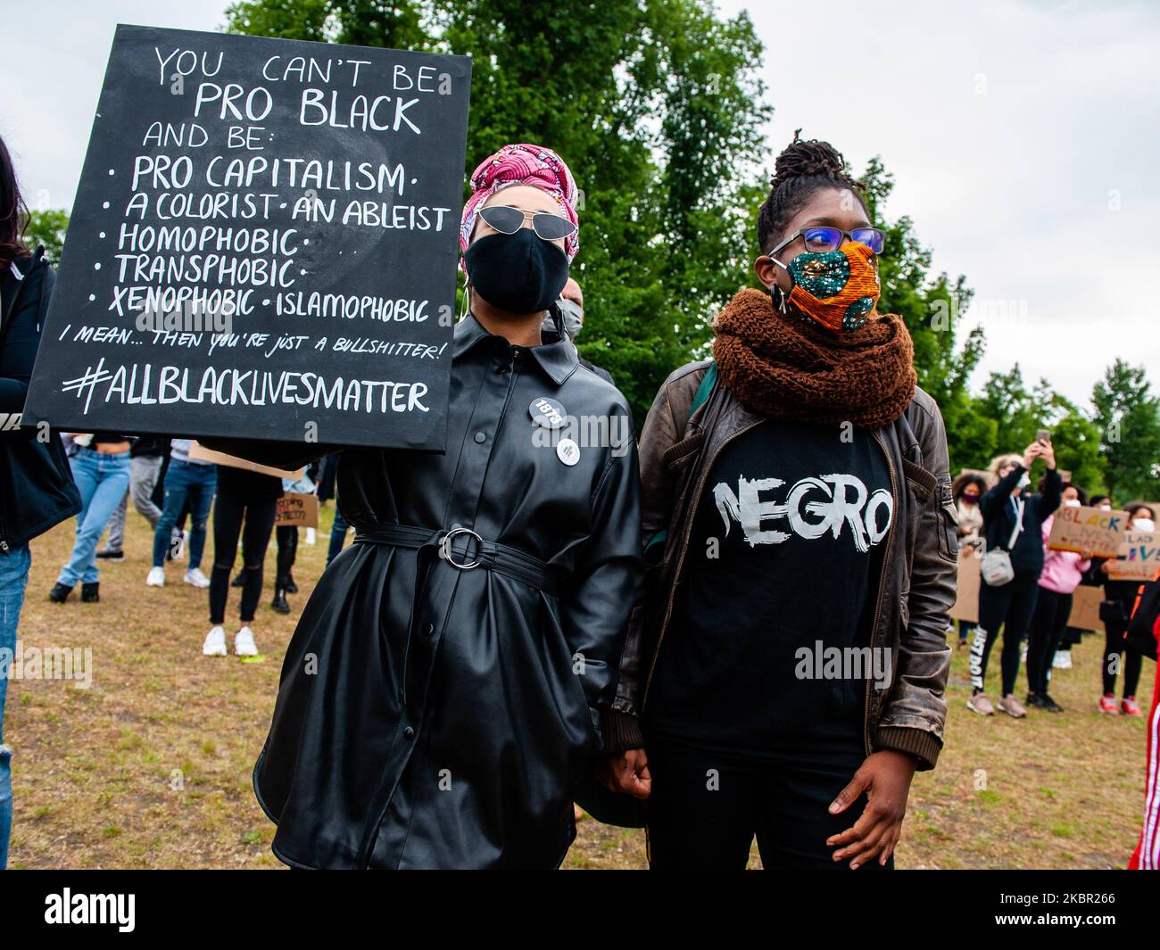Two Black women are holding a big anti racist placard, during the ...