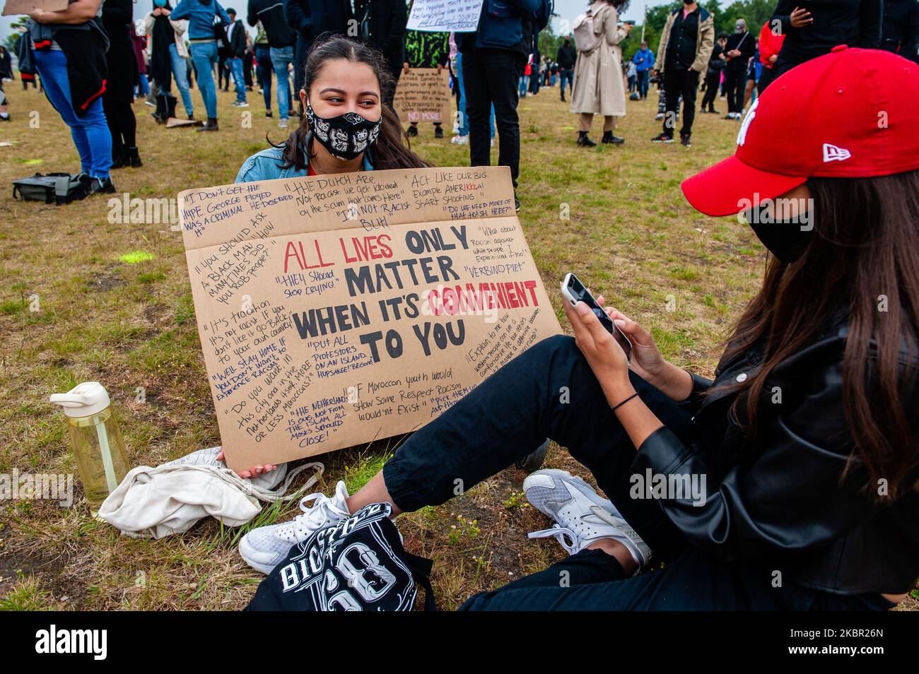 Two white girls are sitting while holding a placard, during the second ...