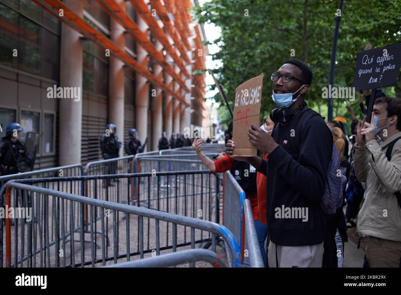 A man holds a placard reading 'Racism kills' in front of riot police ...
