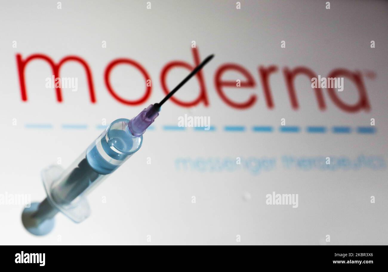 Medical syringe is seen with Moderna company logo displayed on a screen ...