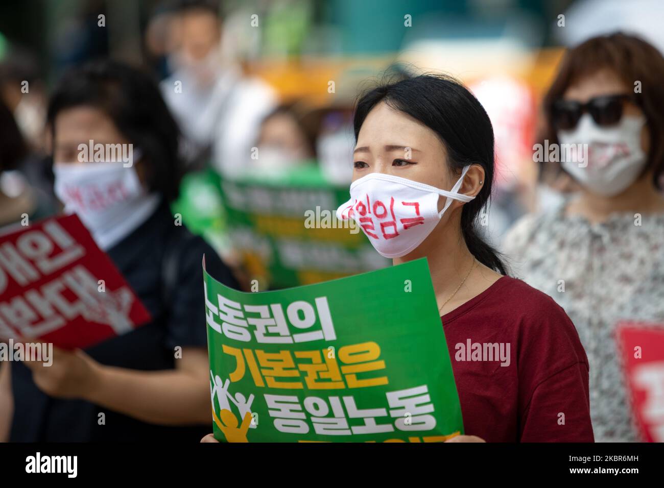 A worker of Seoul Children's Center holds a placard that says 'same ...