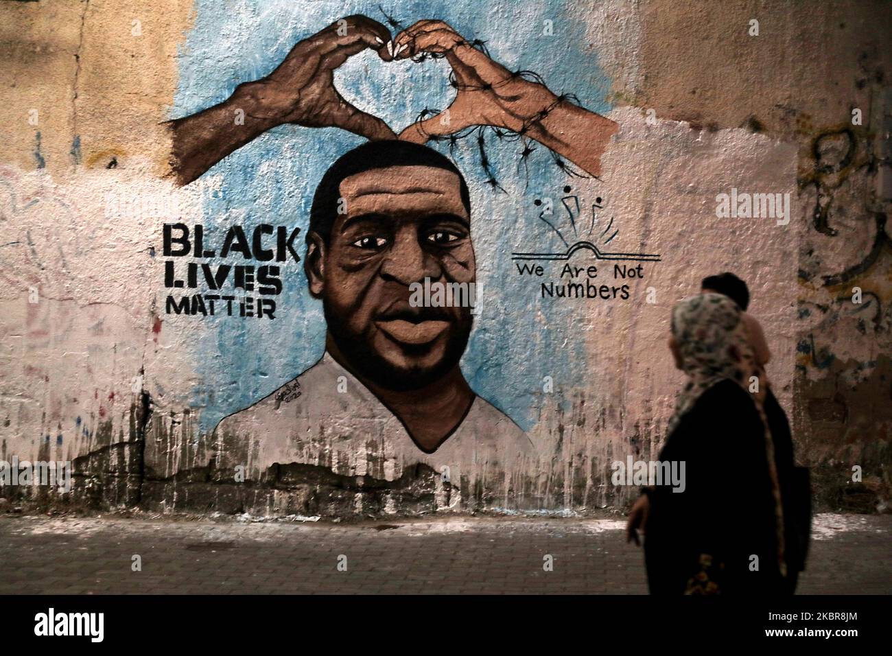 Palestinians walk past a mural of George Floyd, a black American who ...