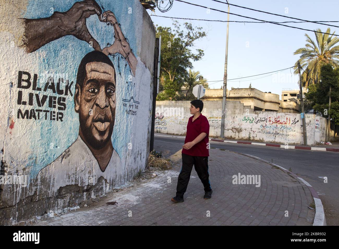 A Palestinian youth walks infront of paints a mural that depicts George ...