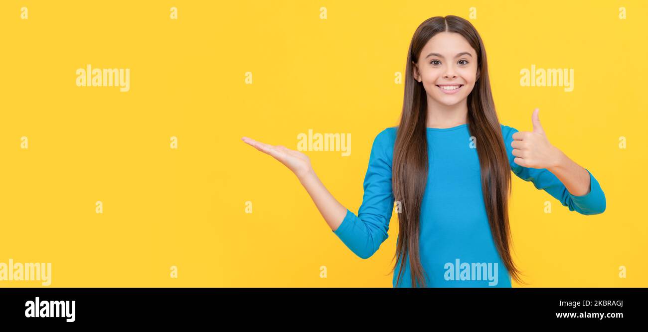 happy kid with thumb up presenting product on yellow background with ...