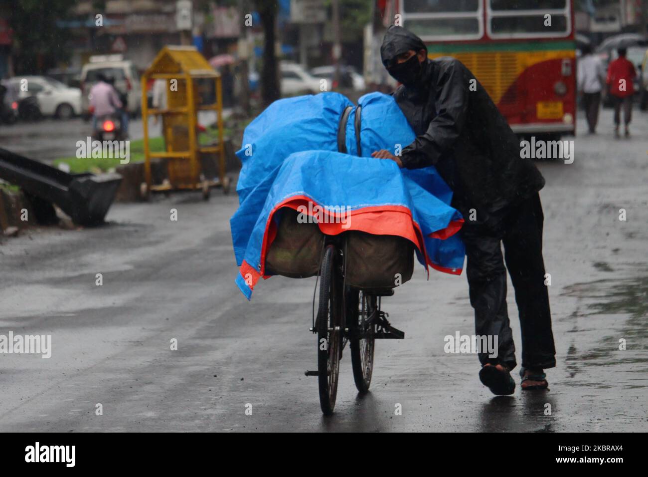 A man pushes his bicycle loaded with goods during heavy rains in Mumbai ...