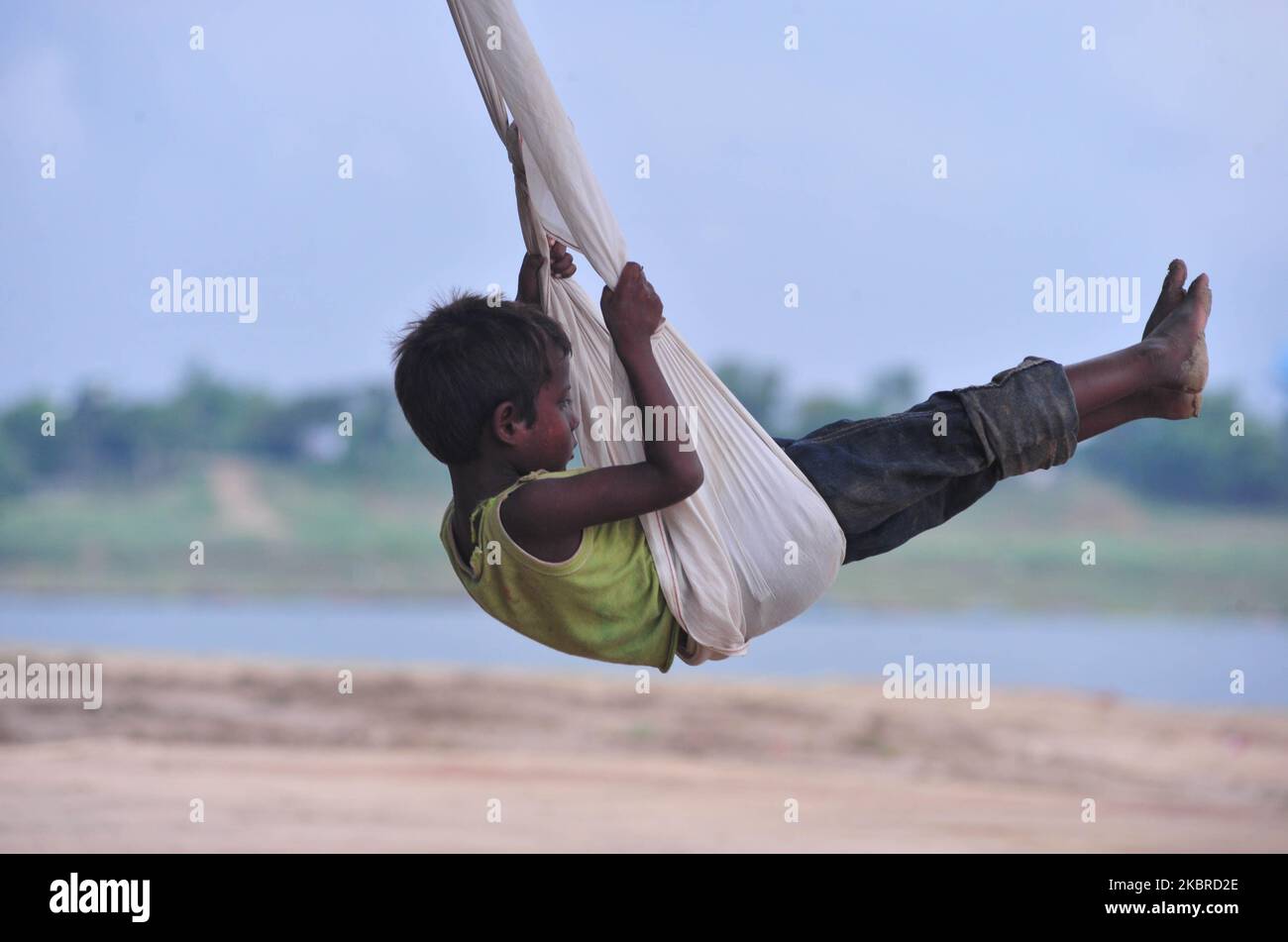 A boy enjoys in swinging rope , on the banks of Yamuna river in ...
