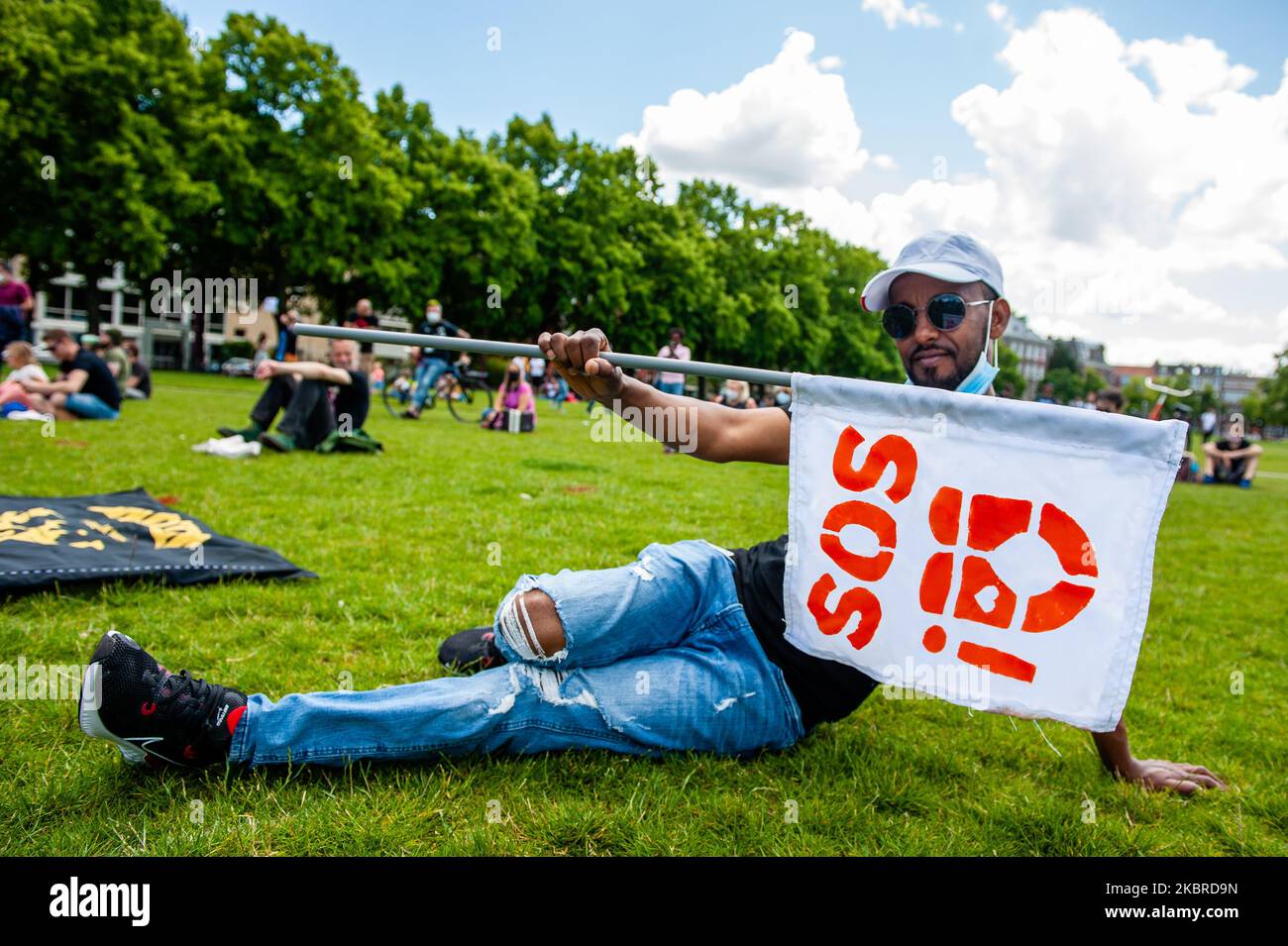 A man is holding a SOS flag, during the Refugee Lives Matter ...