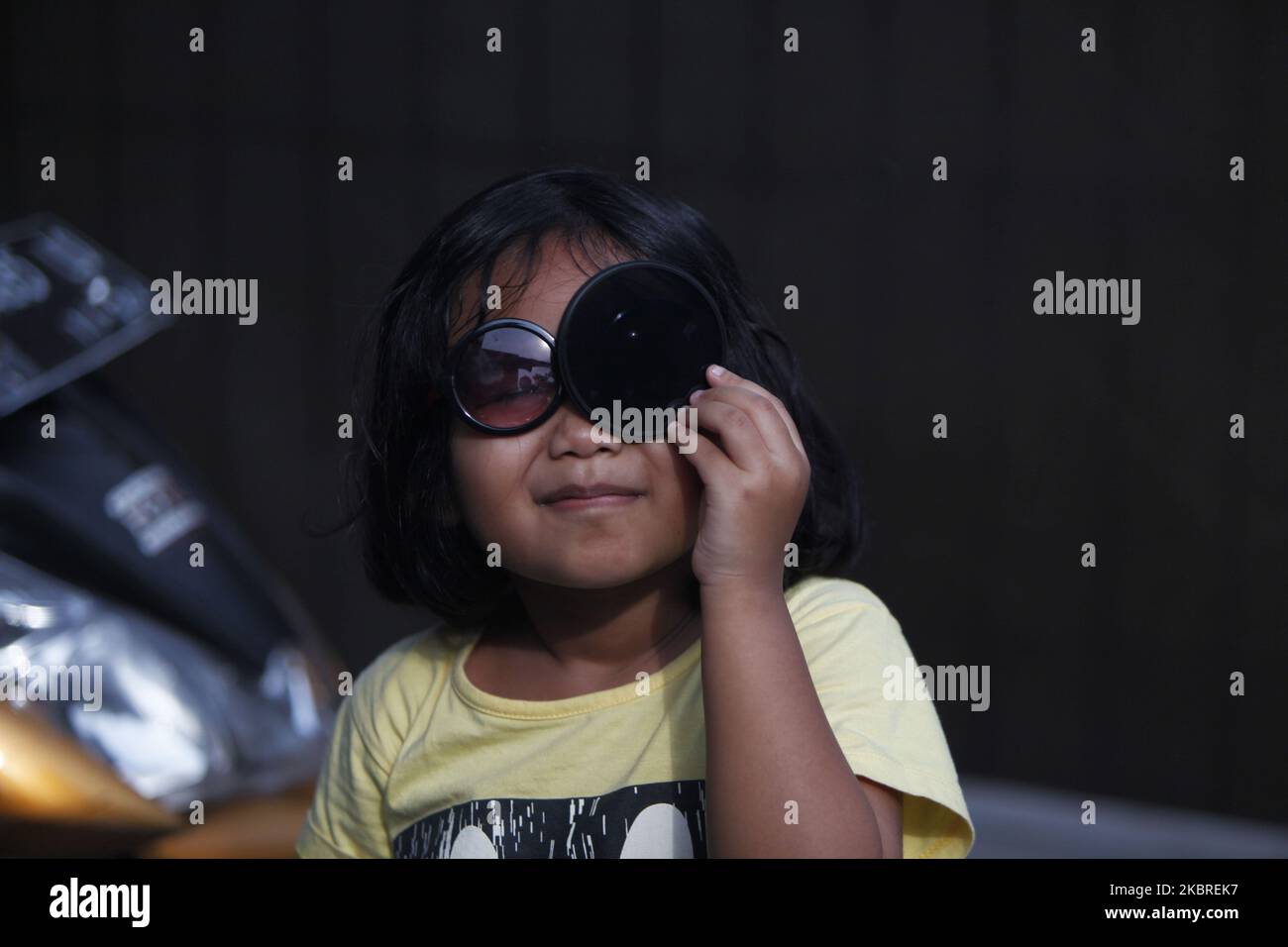 A girl watches the solar eclipse using a lens filter camera in Bogor ...