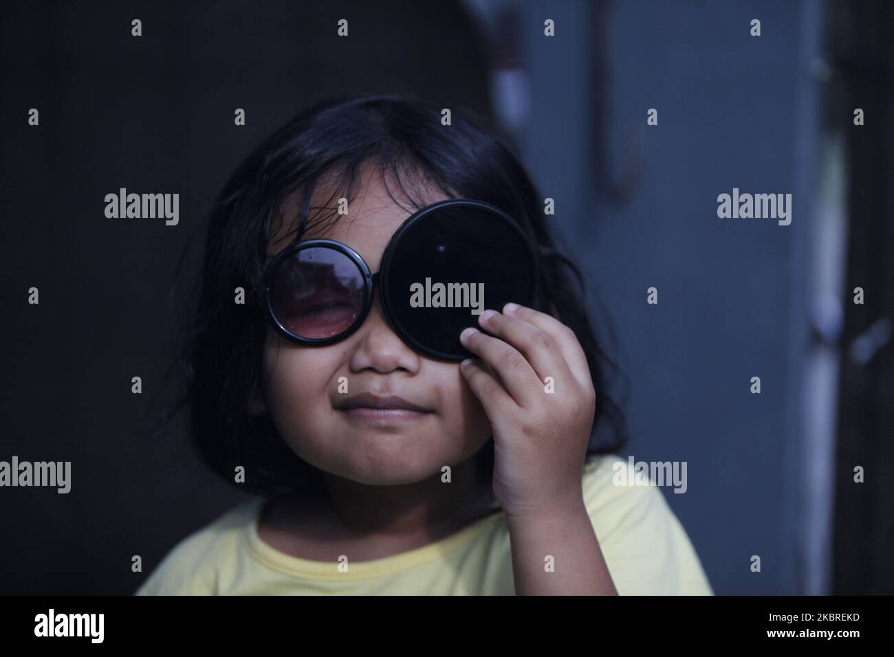 A girl watches the solar eclipse using a lens filter camera in Bogor ...