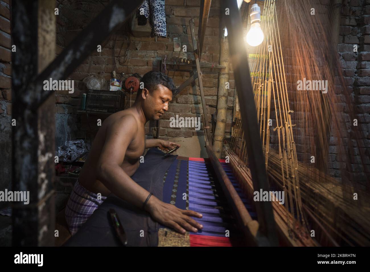 Handloom weaver weaves Banarasi saree on a traditional wooden hand weaving loom factory at ...