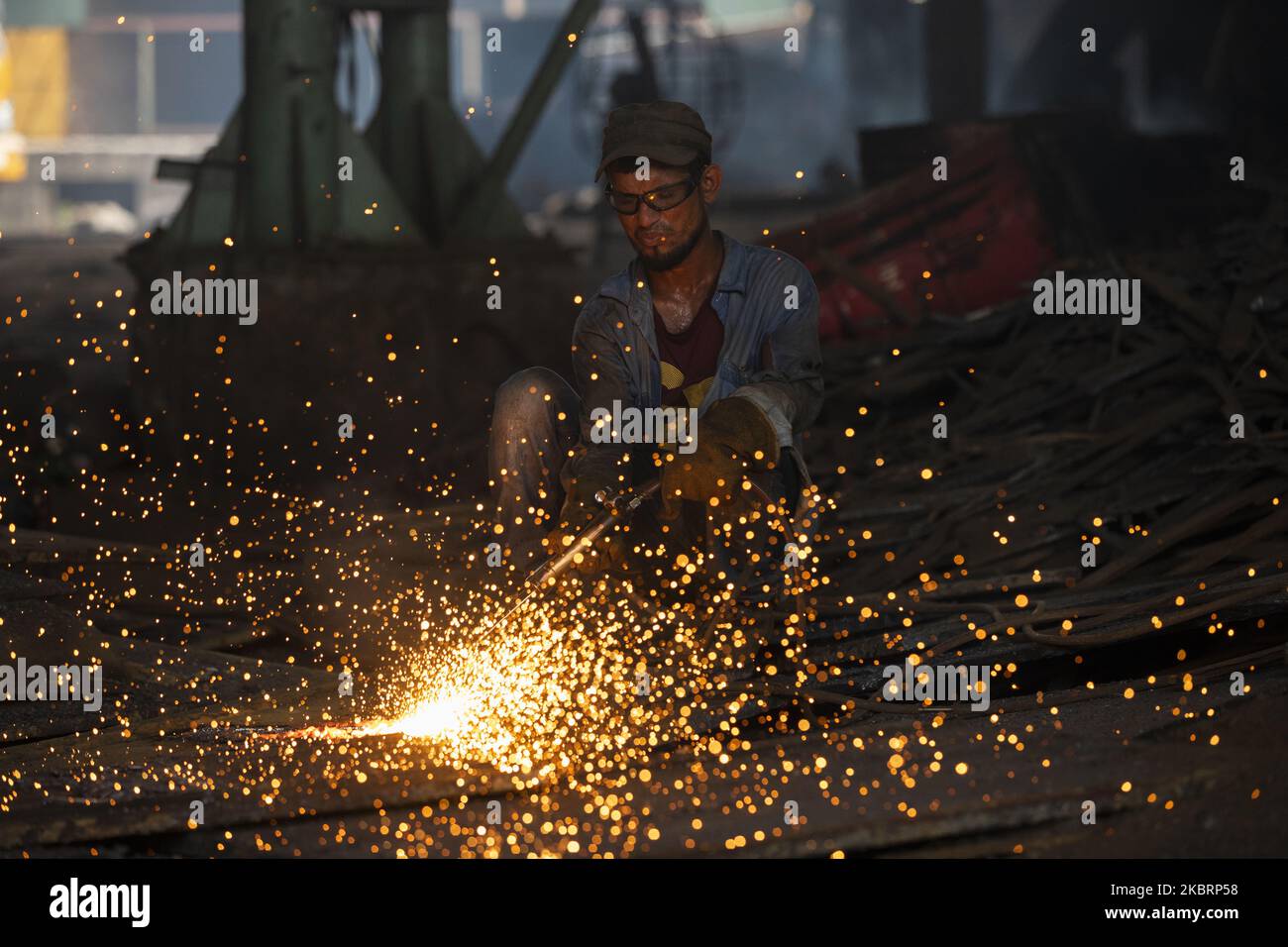 A still re-rolling worker cuts a metal plate with gas flame in Narayanganj, on the outskirts of ...