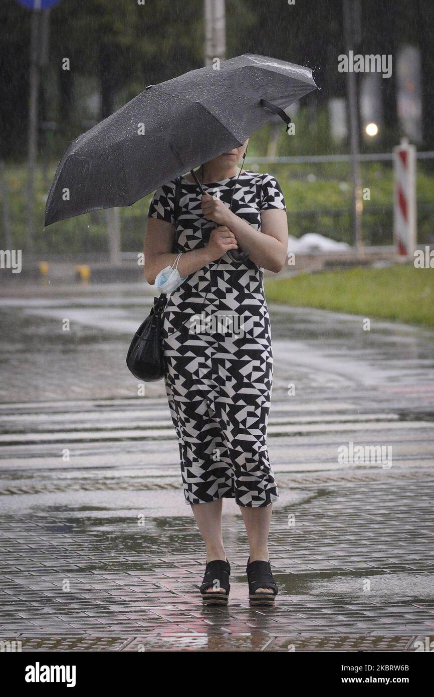 A woman with an umbrella is seen at a traffic stop on June 29, 2020 in ...