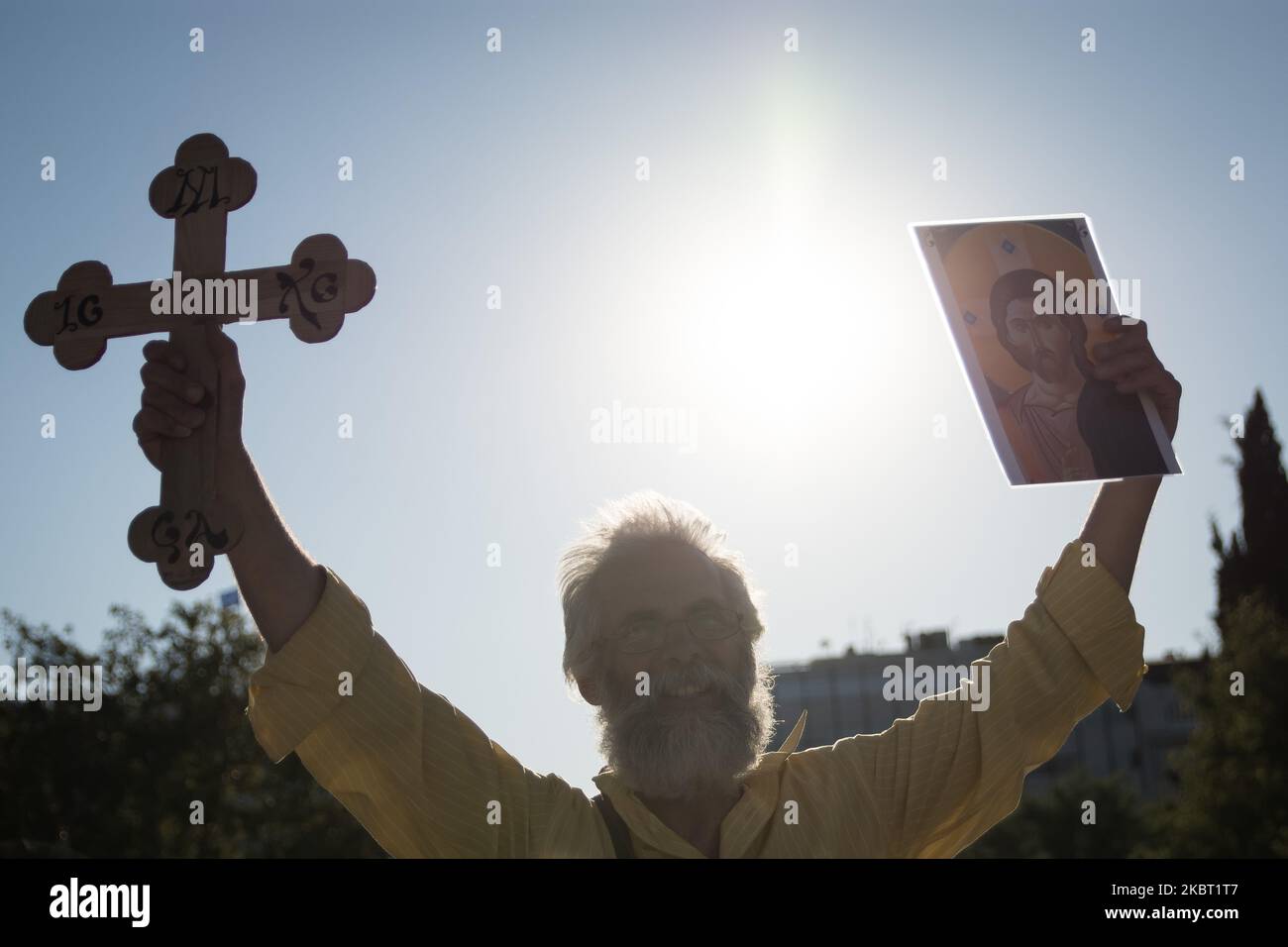 A man is holding a wooden cross and a picture of Jesus at Syntagma ...