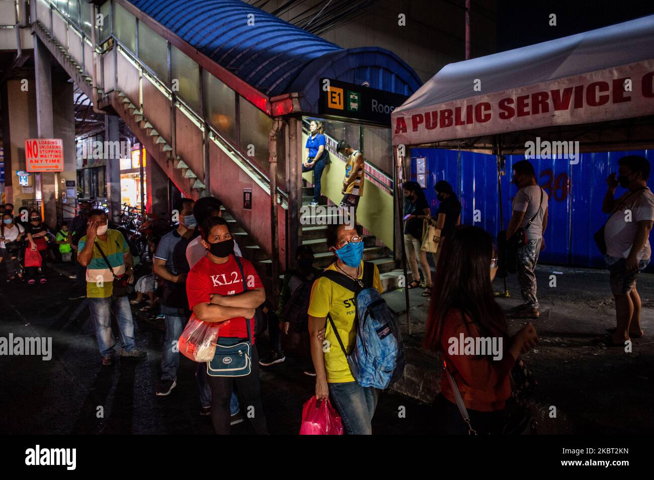 Commuters waiting for buses queue along a major thoroughfare in Quezon ...