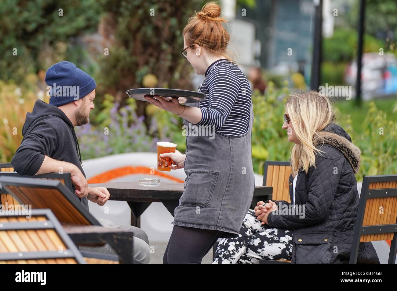 A waiter bring to a customer his order during the re-opening of pubs ...