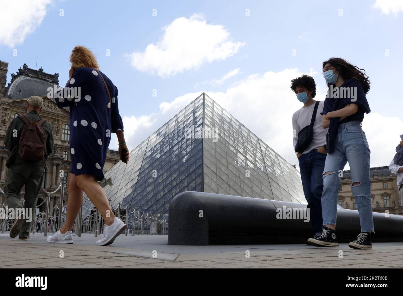 Visitors queue observing social distancing markings outside the Louvre museum as it reopens its ...