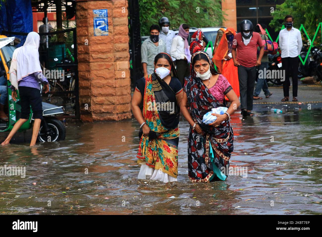Commuters pass through a waterlogged street following heavy rain, in ...