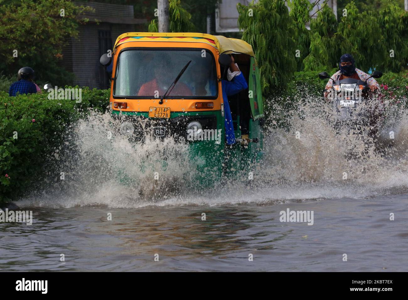 Commuters pass through a waterlogged street following heavy rain, in ...