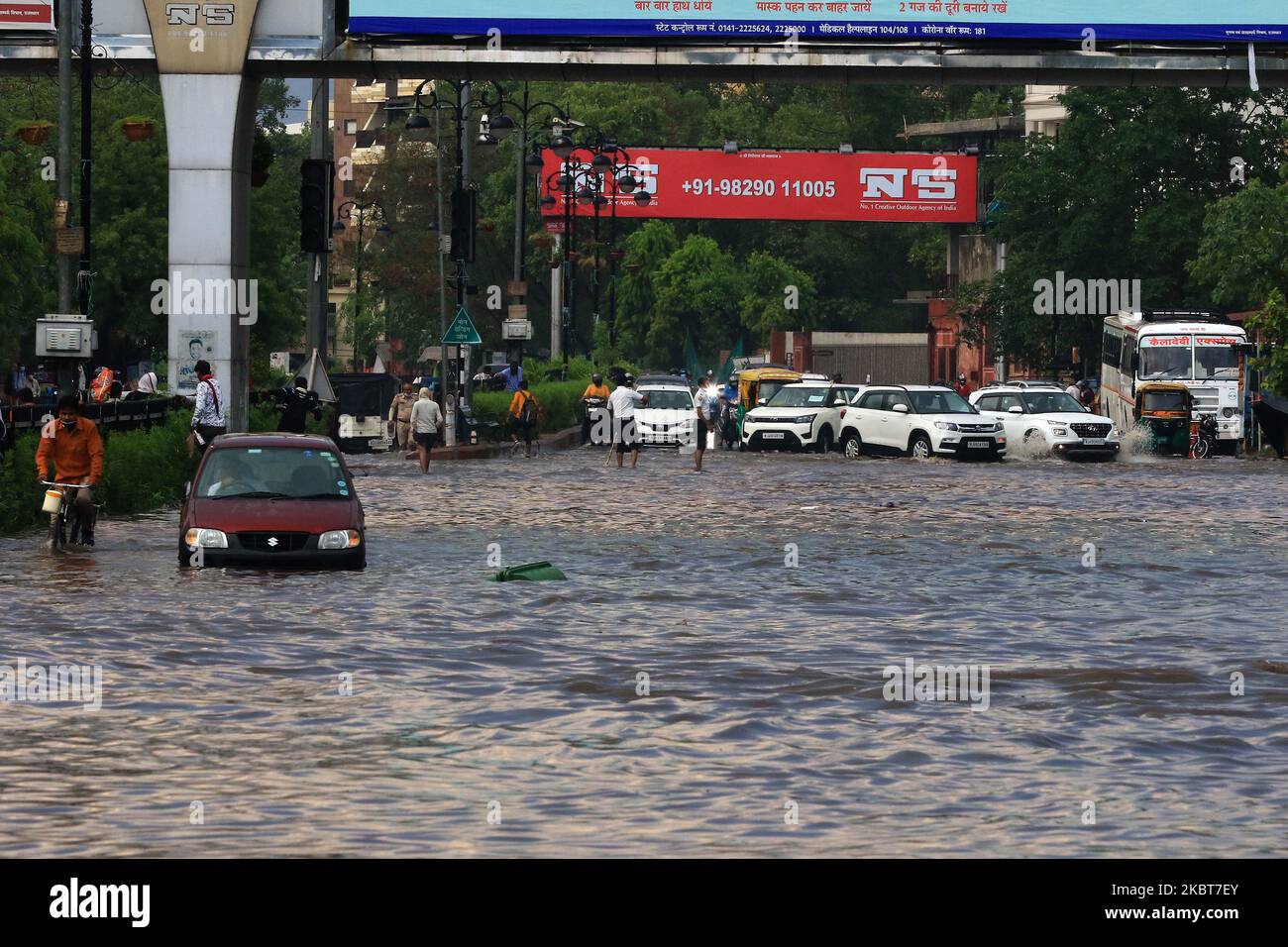 Commuters pass through a waterlogged street following heavy rain, in ...