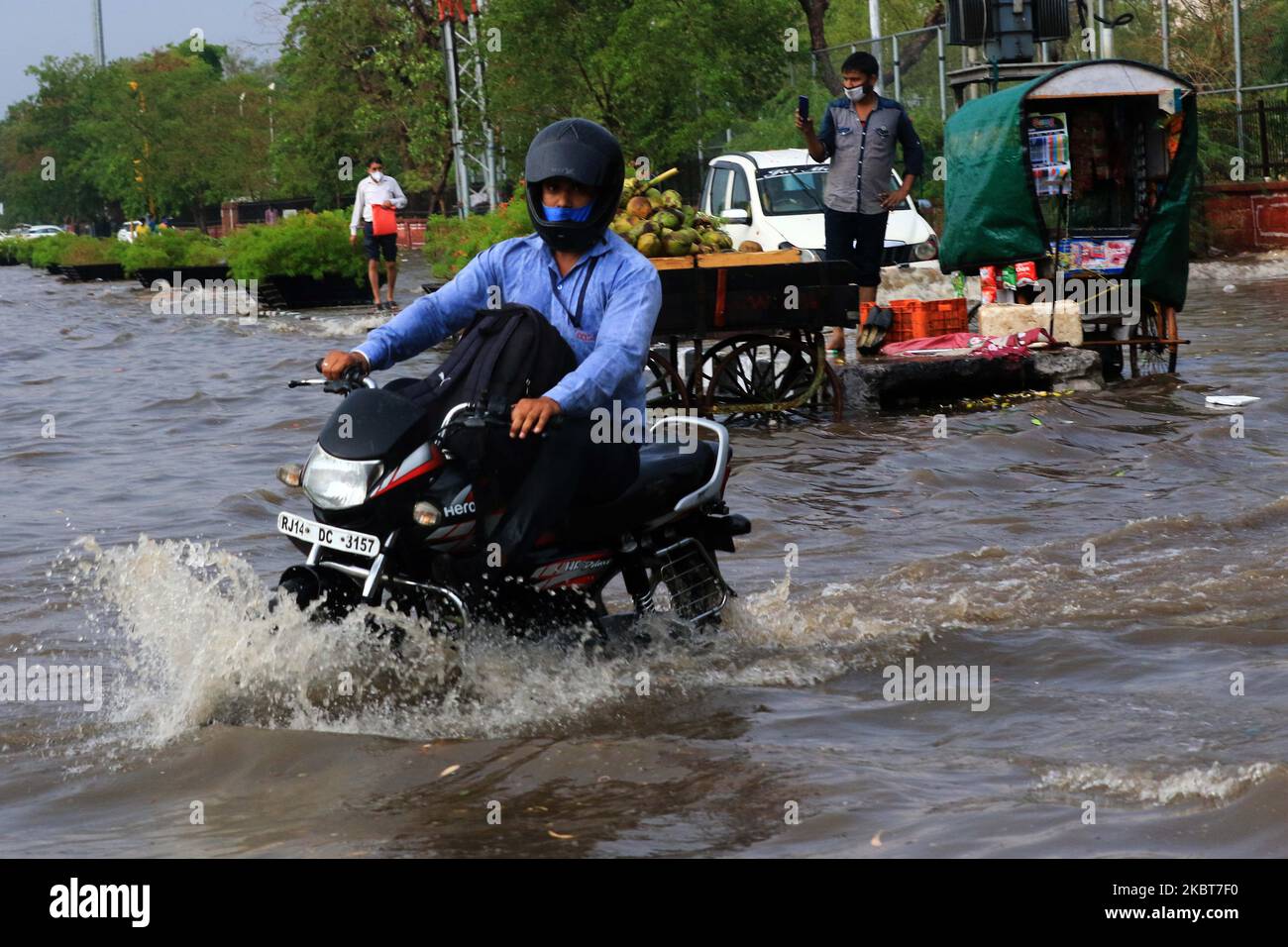 Commuters pass through a waterlogged street following heavy rain, in ...