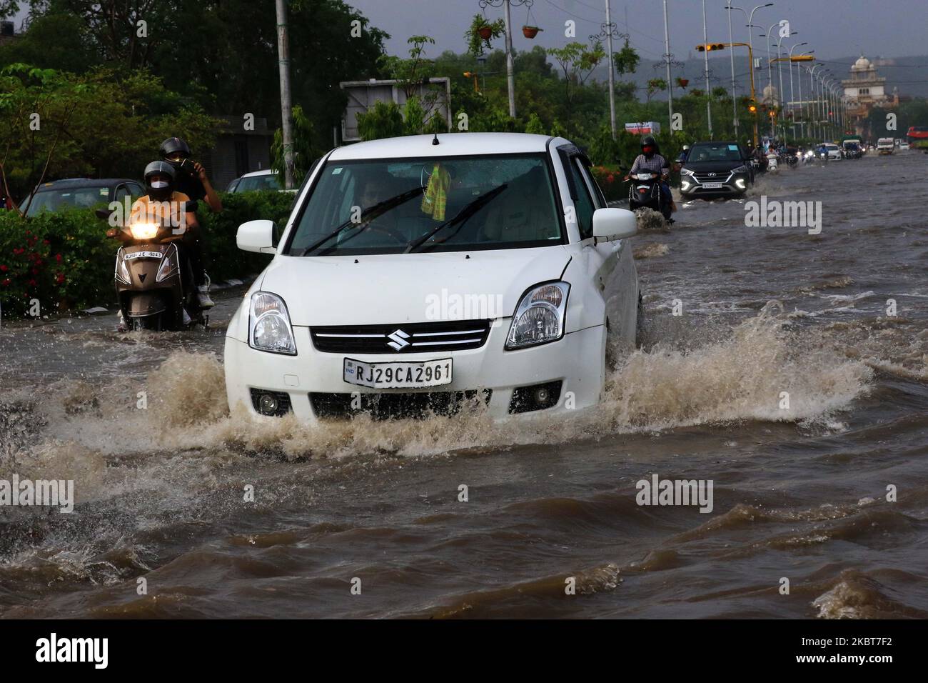 Commuters pass through a waterlogged street following heavy rain, in ...