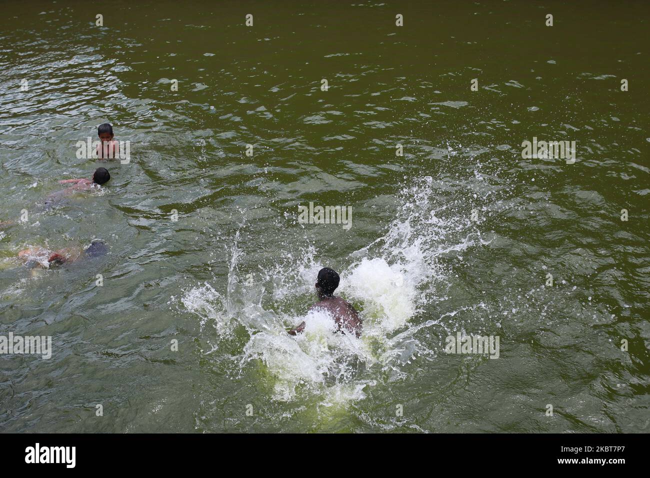 Children bathe in a lake during a hot summer day in Dhaka, Bangladesh ...