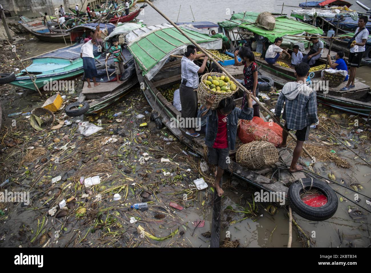 A worker unloads a basket full of mangoes from a boat at Yangon jetty ...