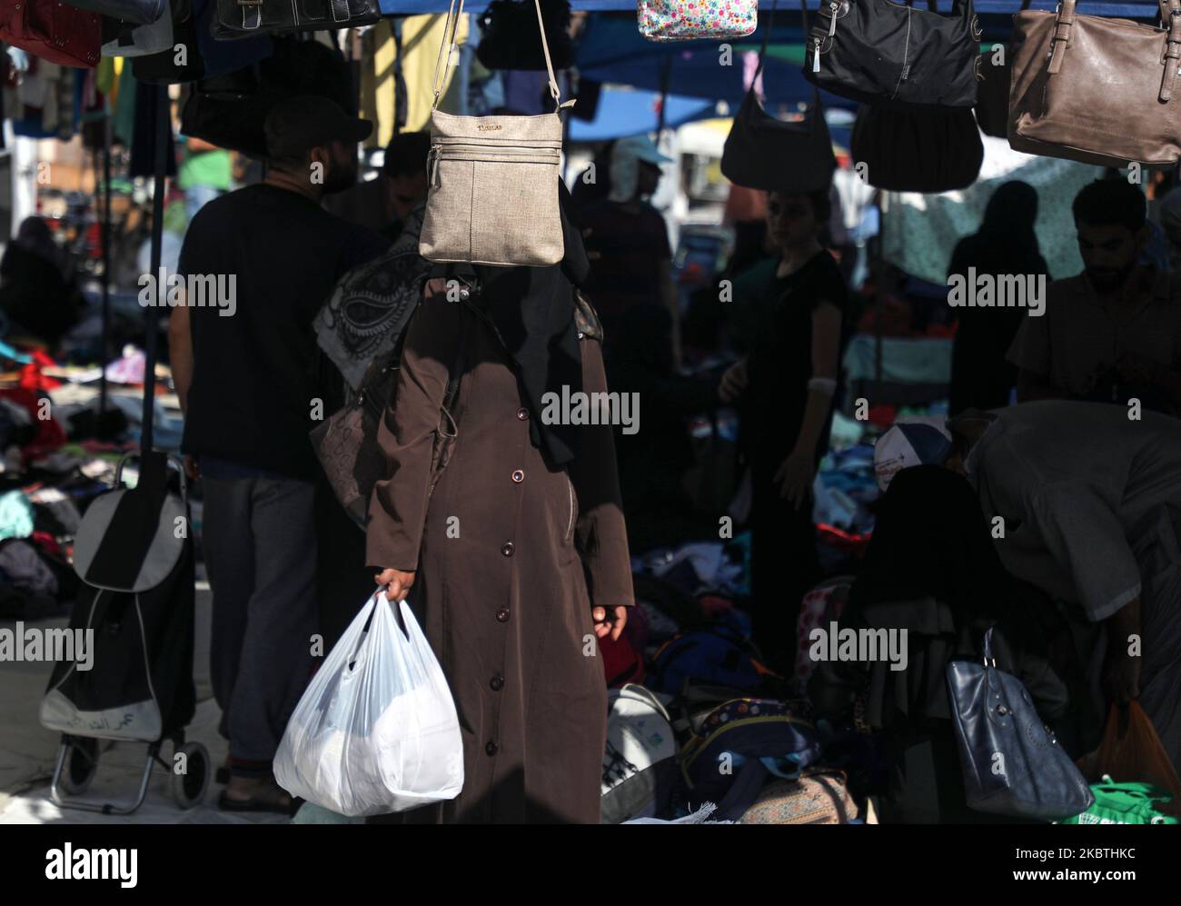 A Palestinian woman shops at a stall in an outdoors market which has ...
