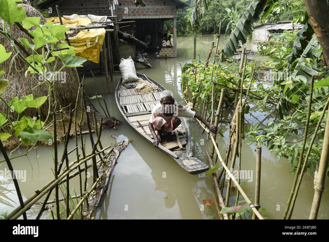 A resident uses a country boat to move across a flooded area in ...
