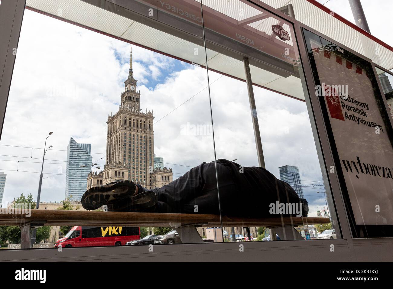 A homeless man is seen sleeping on a bench at a bus stop in the centre ...