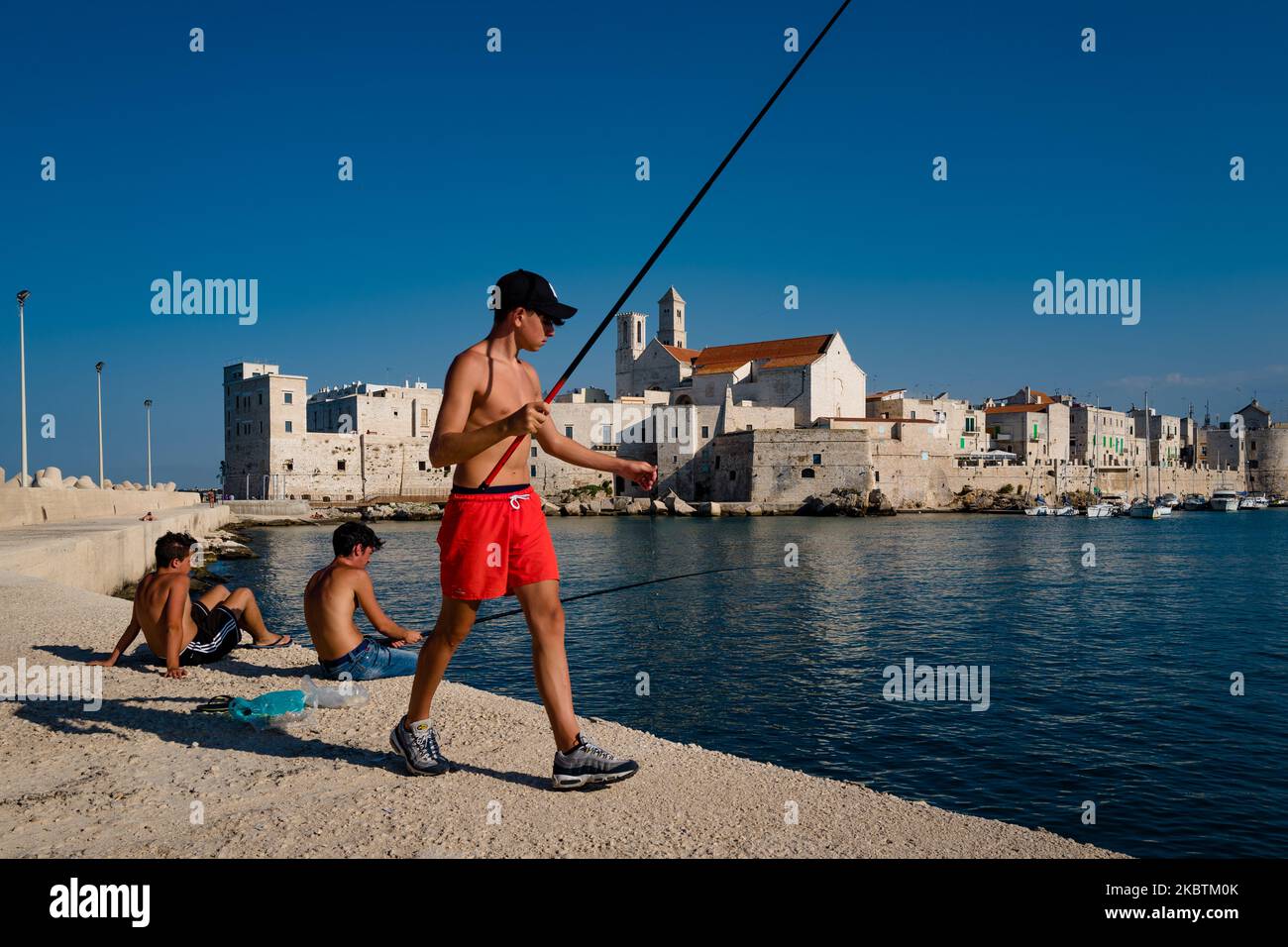 Boys fish on the small port of Giovinazzo on 14 July 2020 in Giovinazzo ...