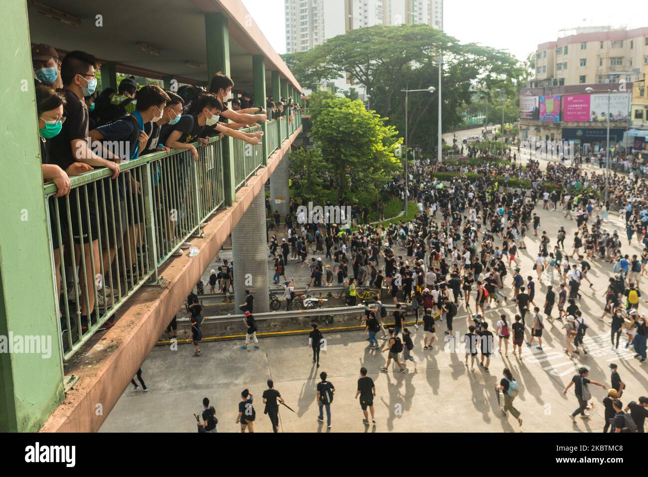 Protesters on a pedestrian overpass signal other protesters to take ...