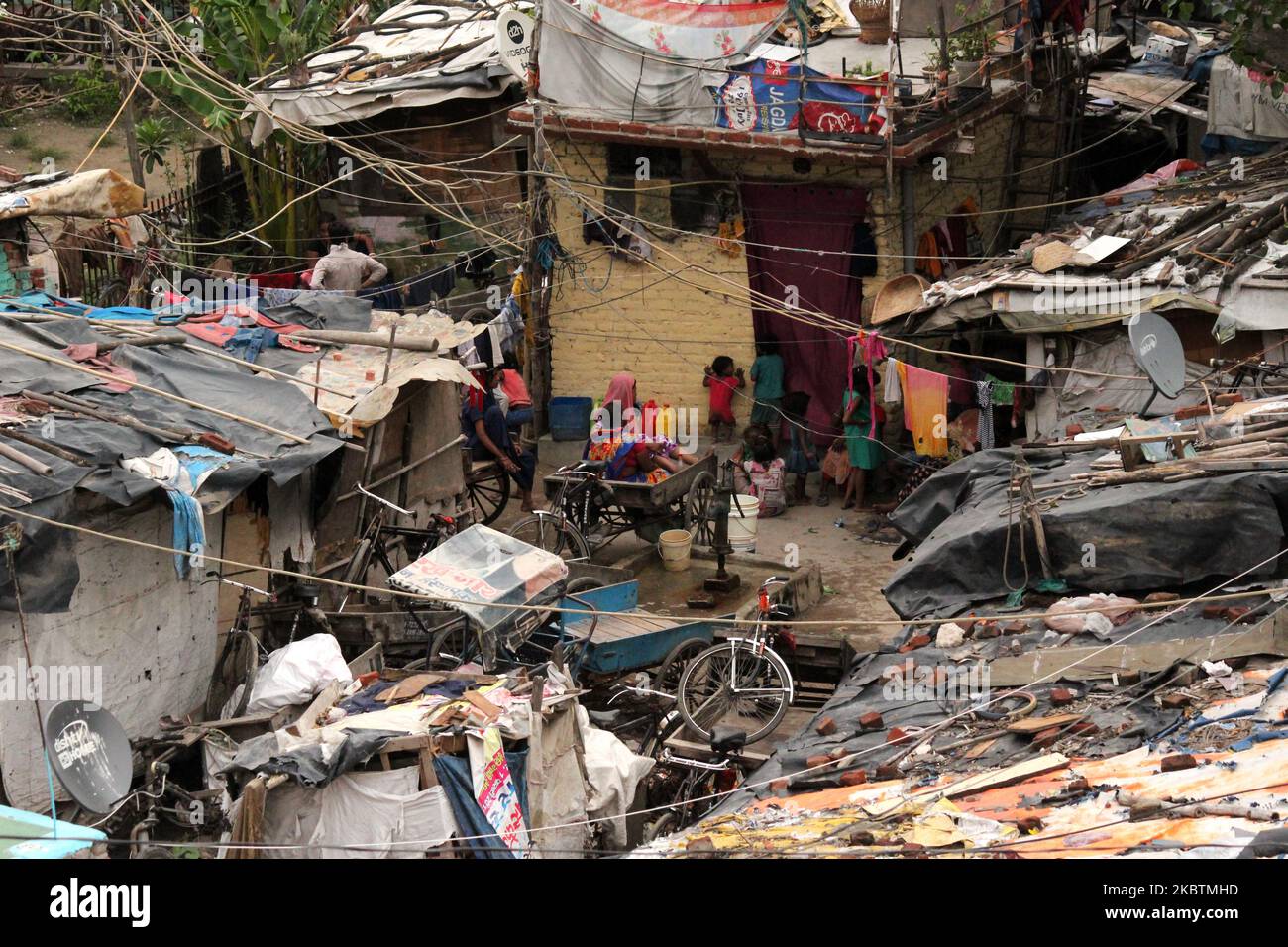 People are seen sitting outside their homes in a congested slum area in ...