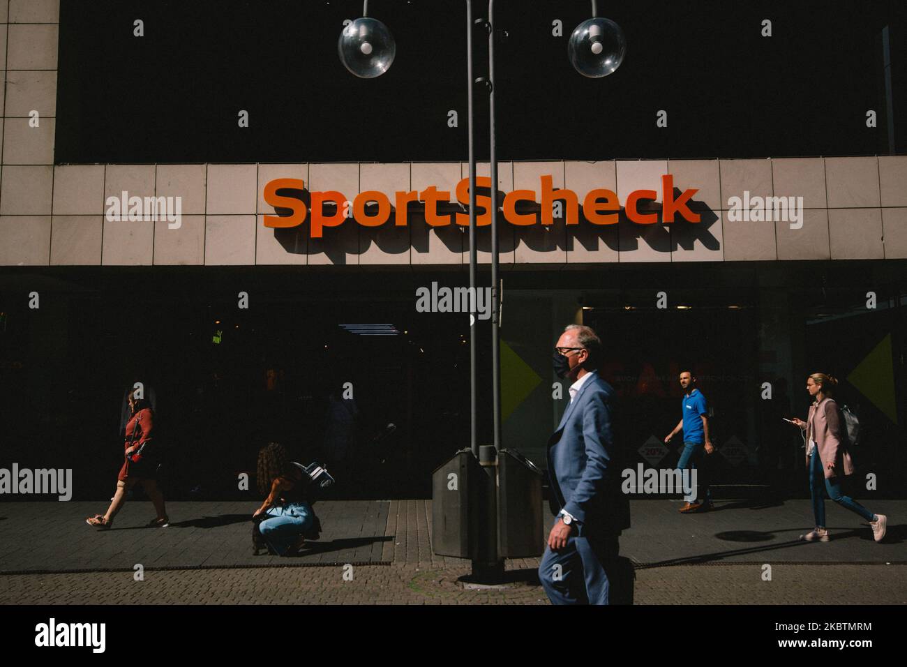 shoppers walk in front of SportScheck retailer store in Cologne ...