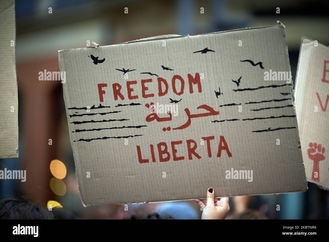 Someone holds a placar dreading 'Freedom' in several languages. Several ...