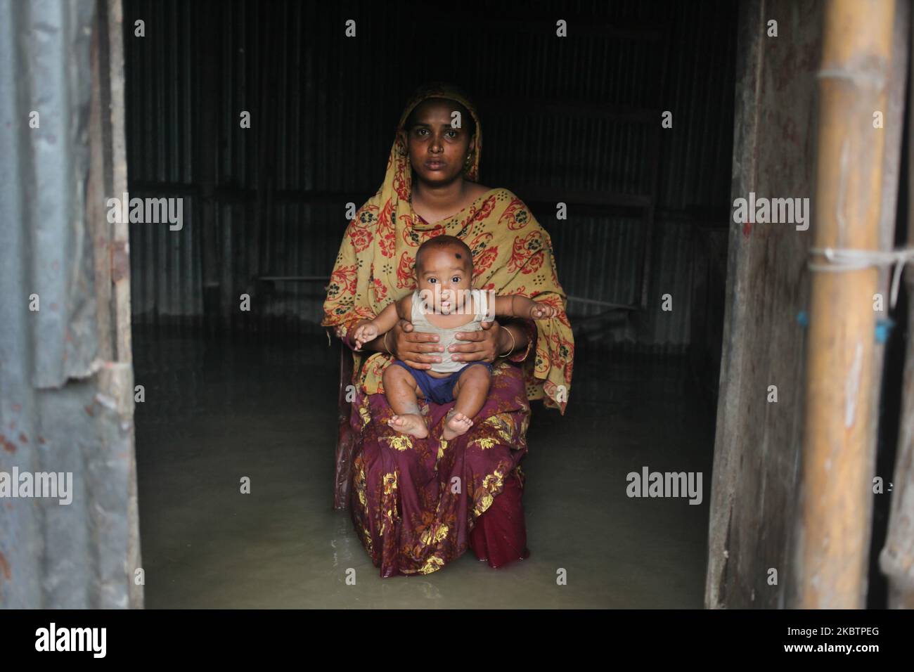Lutfur(23) holds her child as she poses for a photograph inside her water drowned home in ...