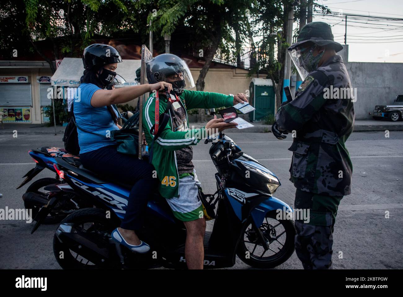 A couple riding a motorcycle presents identification cards proving ...