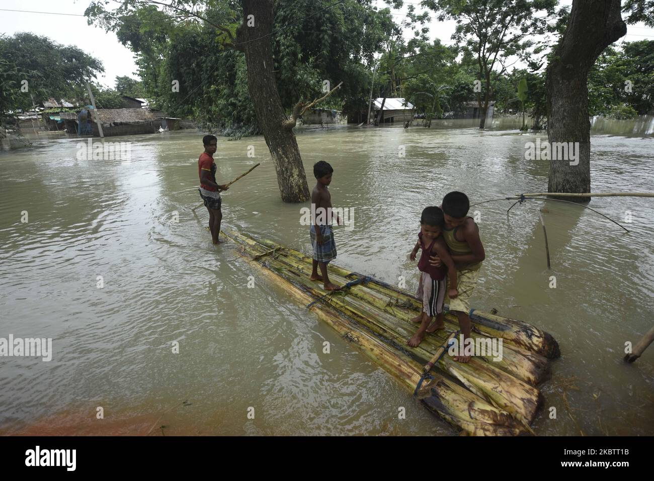 Children uses a banana tree raft to move across a flooded area in a ...