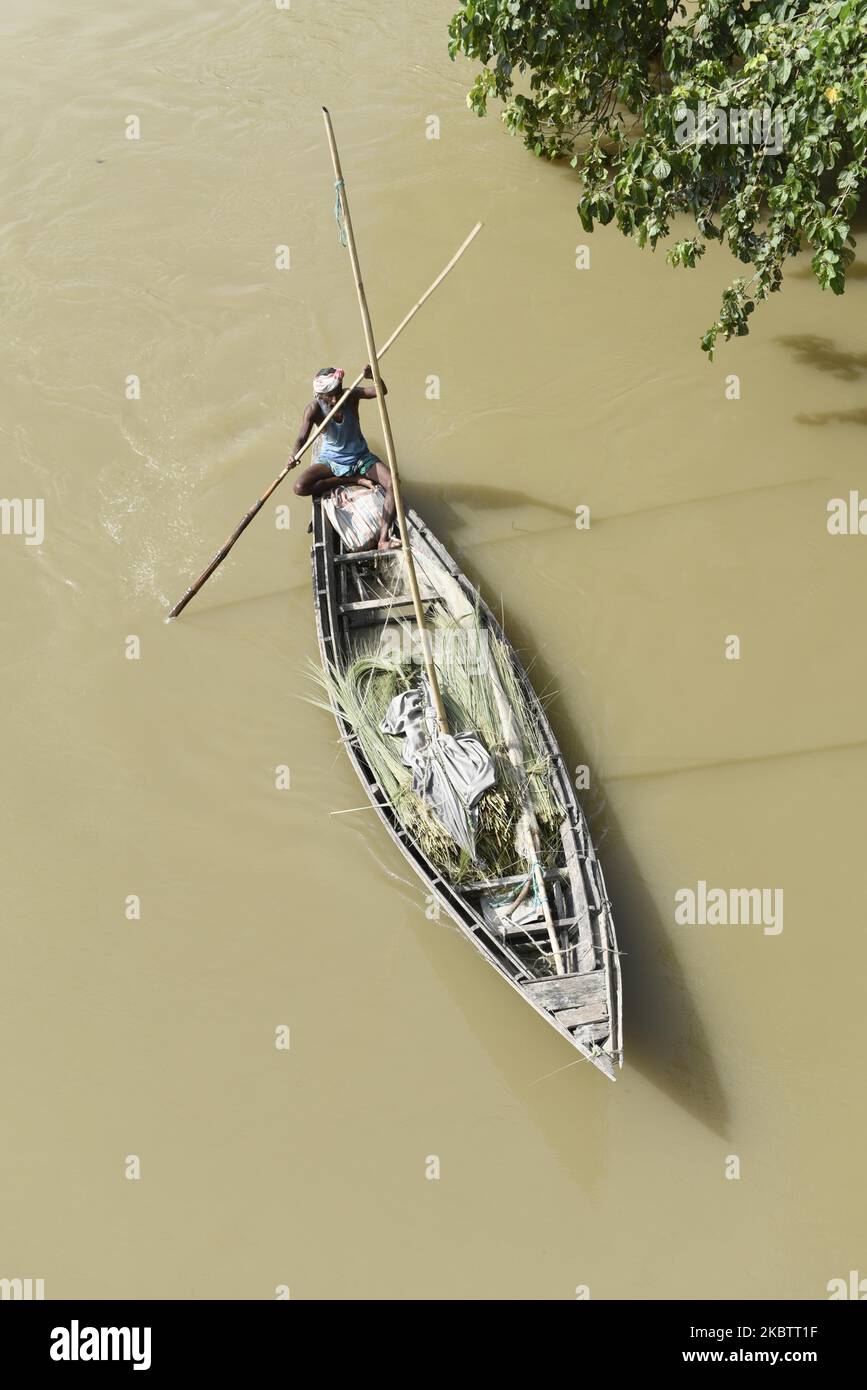 Villager uses a boat to move across a flooded area in a flood effected ...