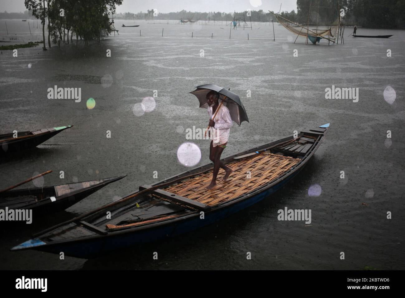 A boatman rides his boat through floodwater during rain in Kurigram ...