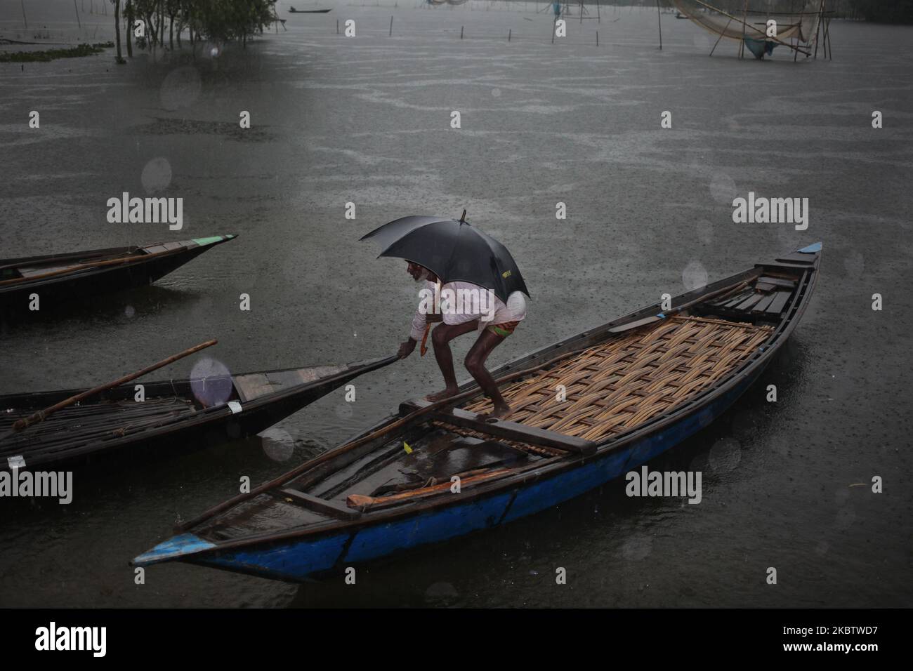 A boatman rides his boat through floodwater during rain in Kurigram ...