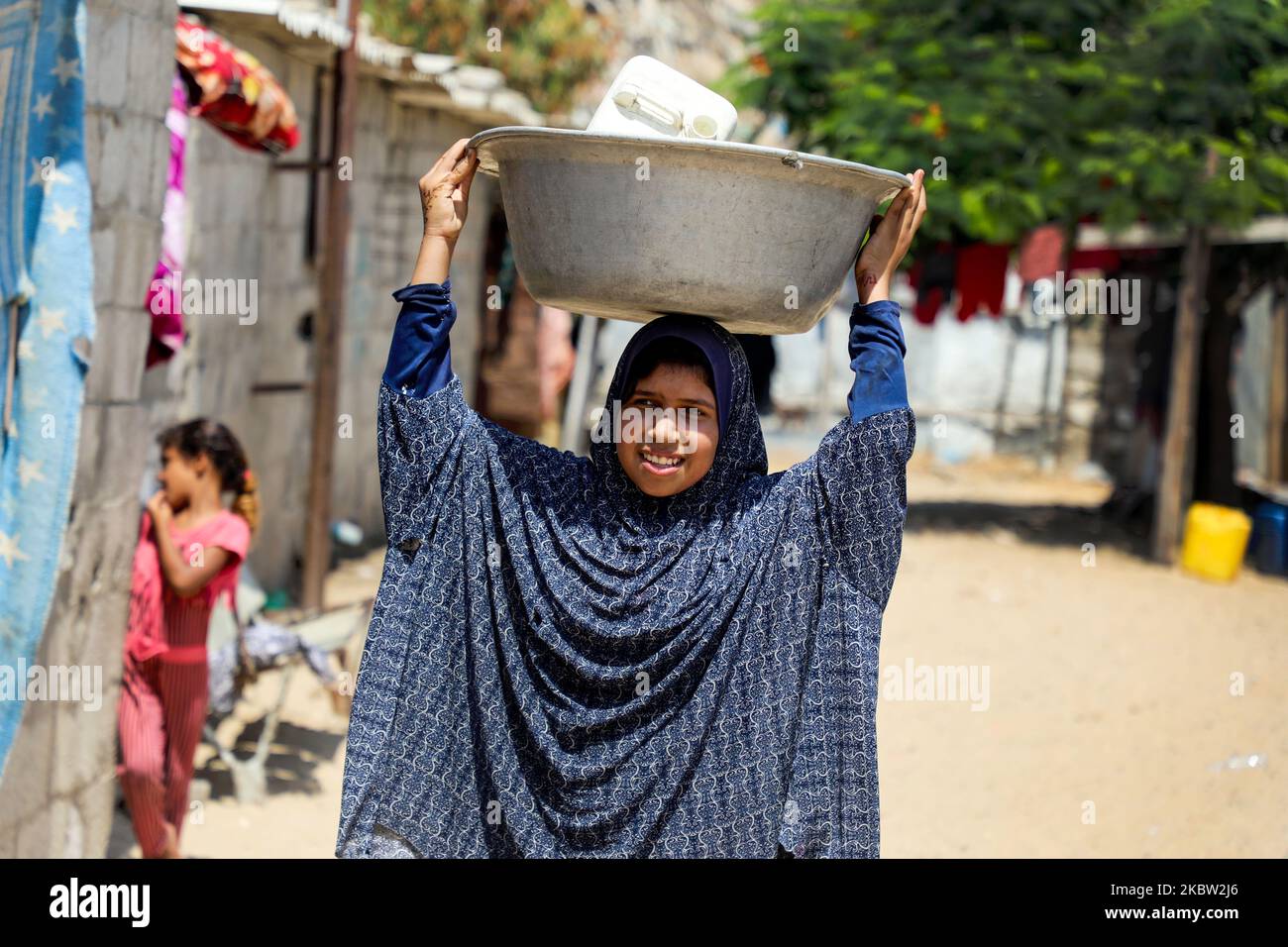 A Palestinian girl fills bottles and cans with drinking water in a slum ...