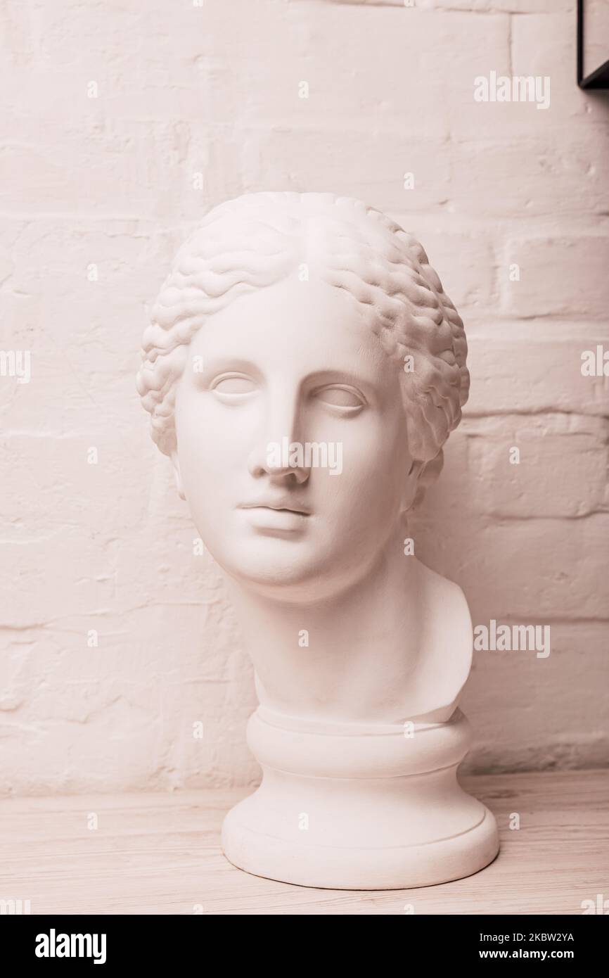Plaster head of the statue against the background of a white brick wall ...