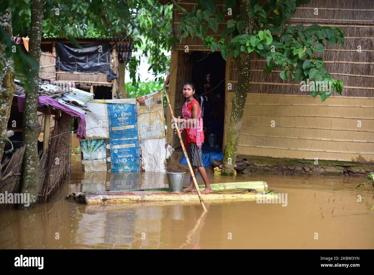 Girls row a makeshift raft past submerged houses at a flood-affected ...