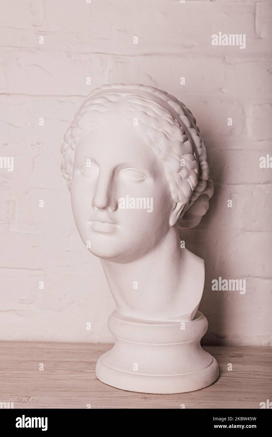 Plaster head of the statue against the background of a white brick wall ...