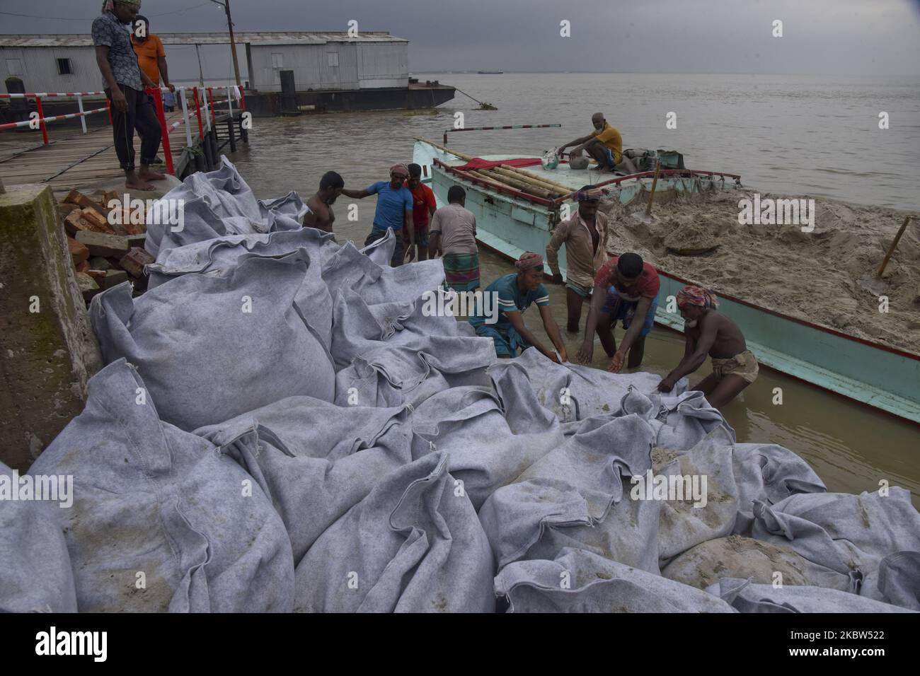 Workers prepare sandbags to repair the embankment designed to protect ...