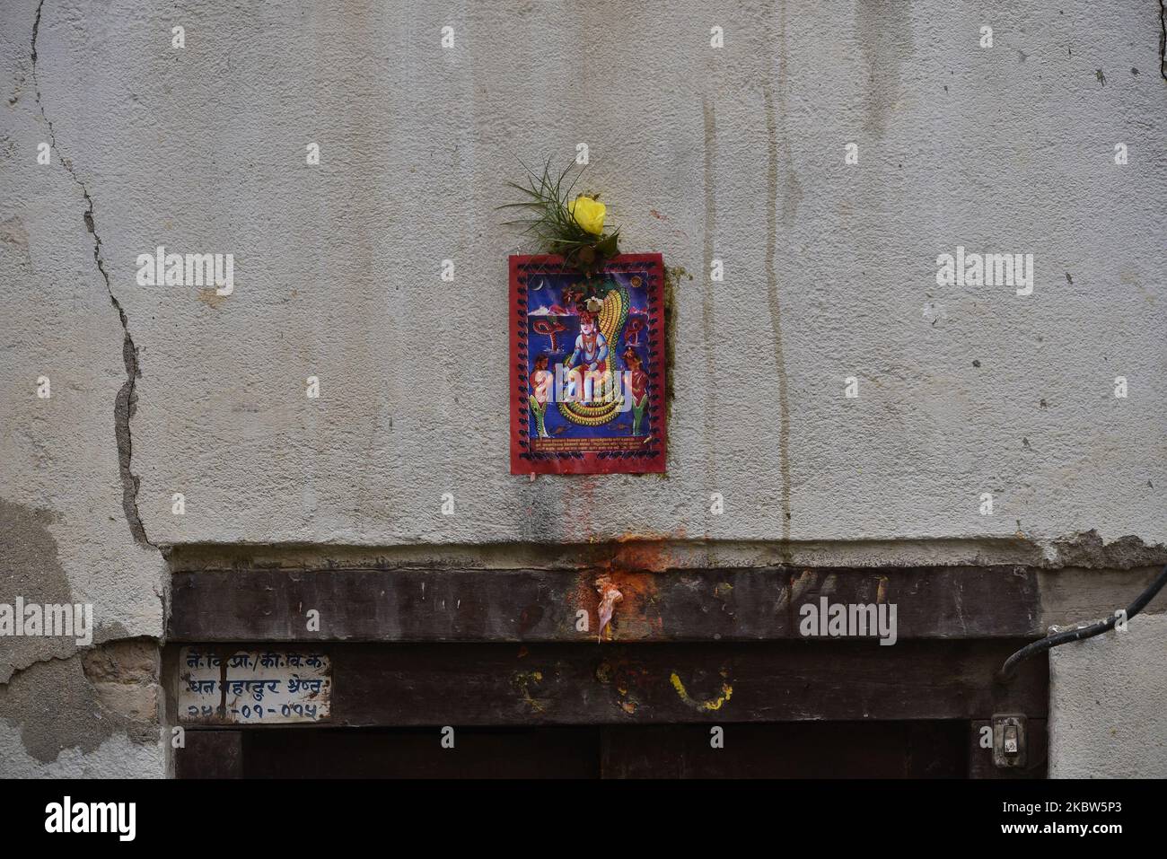 A sticked poster of a snake god at the main entrance of house during ...